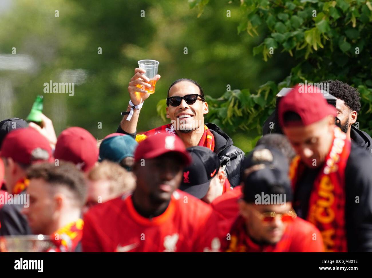 Liverpool's Virgil van Dijk (background) raises a cup in a open-top bus ...