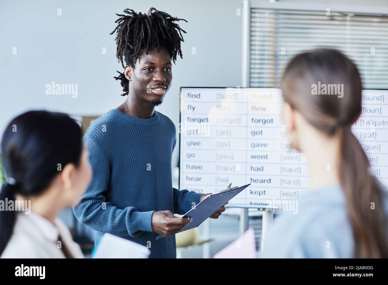 Portrait of black young man in group discussion during English seminar ...