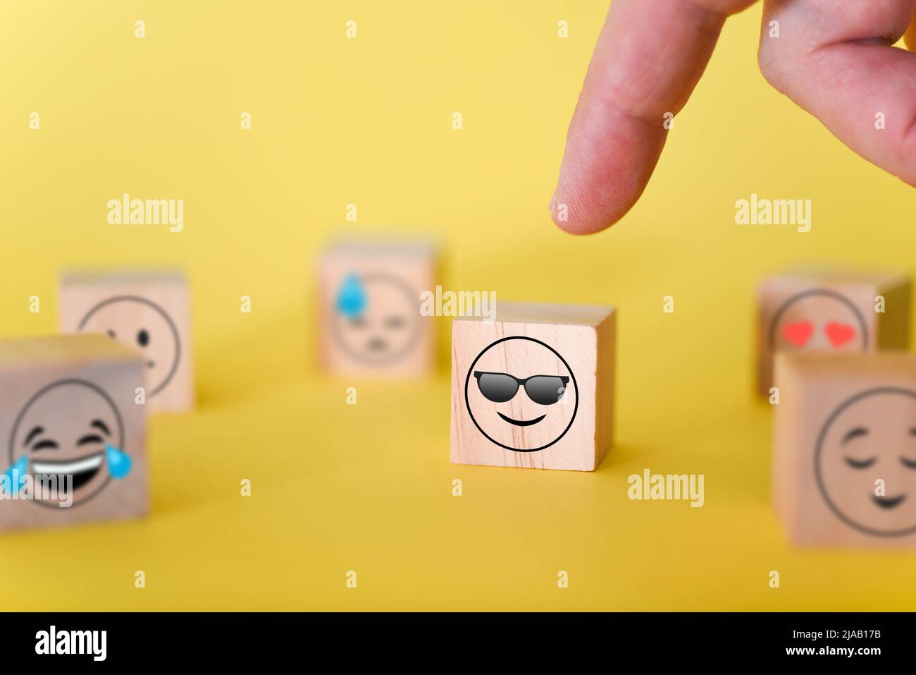 The finger points to a smiley emoji with glasses on a yellow background ...
