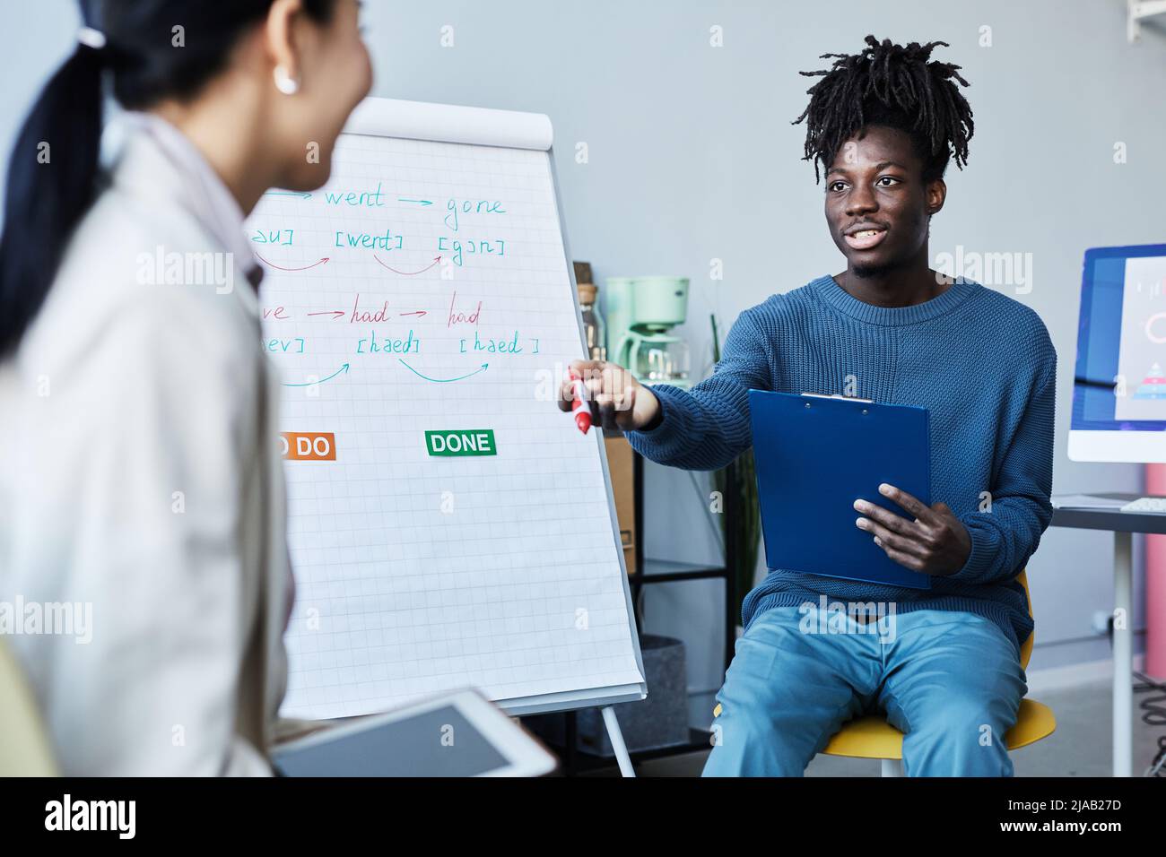 Portrait of young black man leading group discussion during English ...