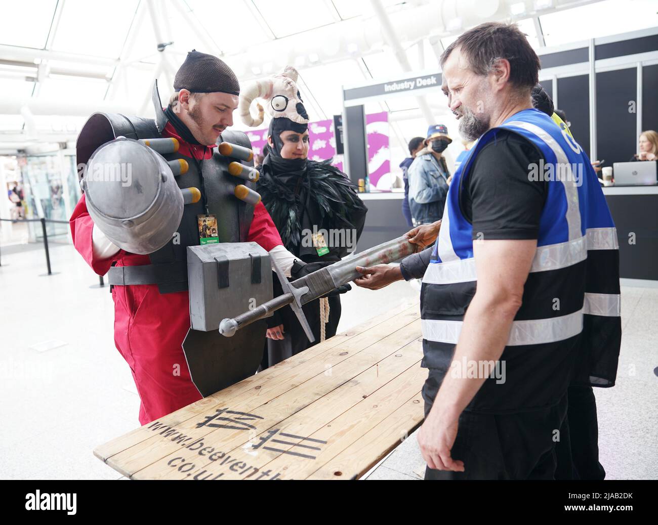 A cosplayer's prop sword is checked by security upon arriving at MCM ...