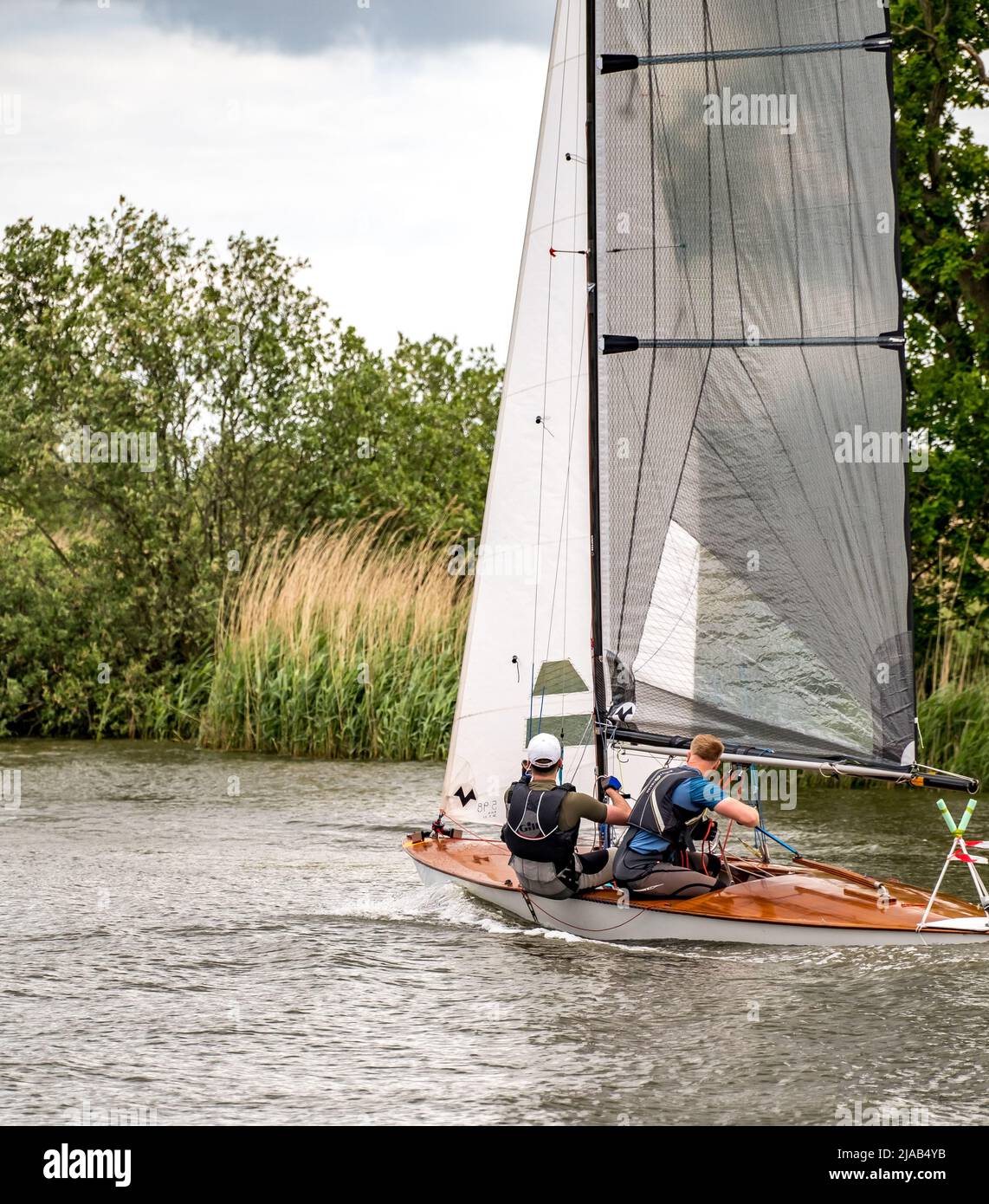 Horning, Norfolk, UK – May 28 2022. Two males on a traditional wooden ...