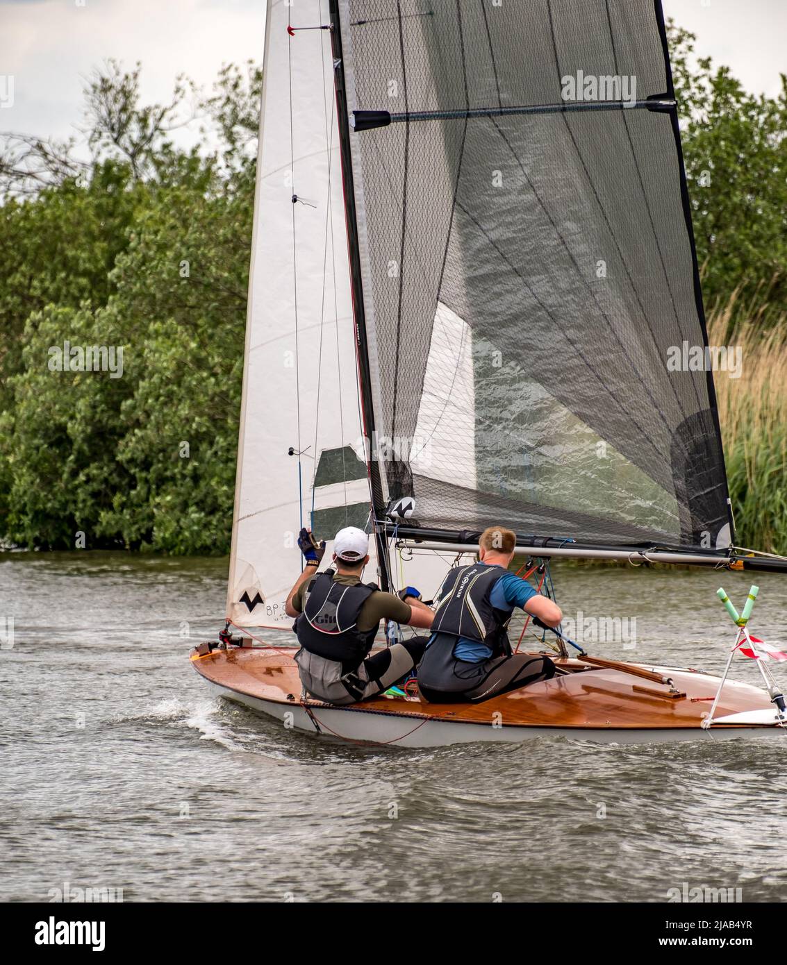 Horning, Norfolk, UK – May 28 2022. Two males on a traditional wooden ...