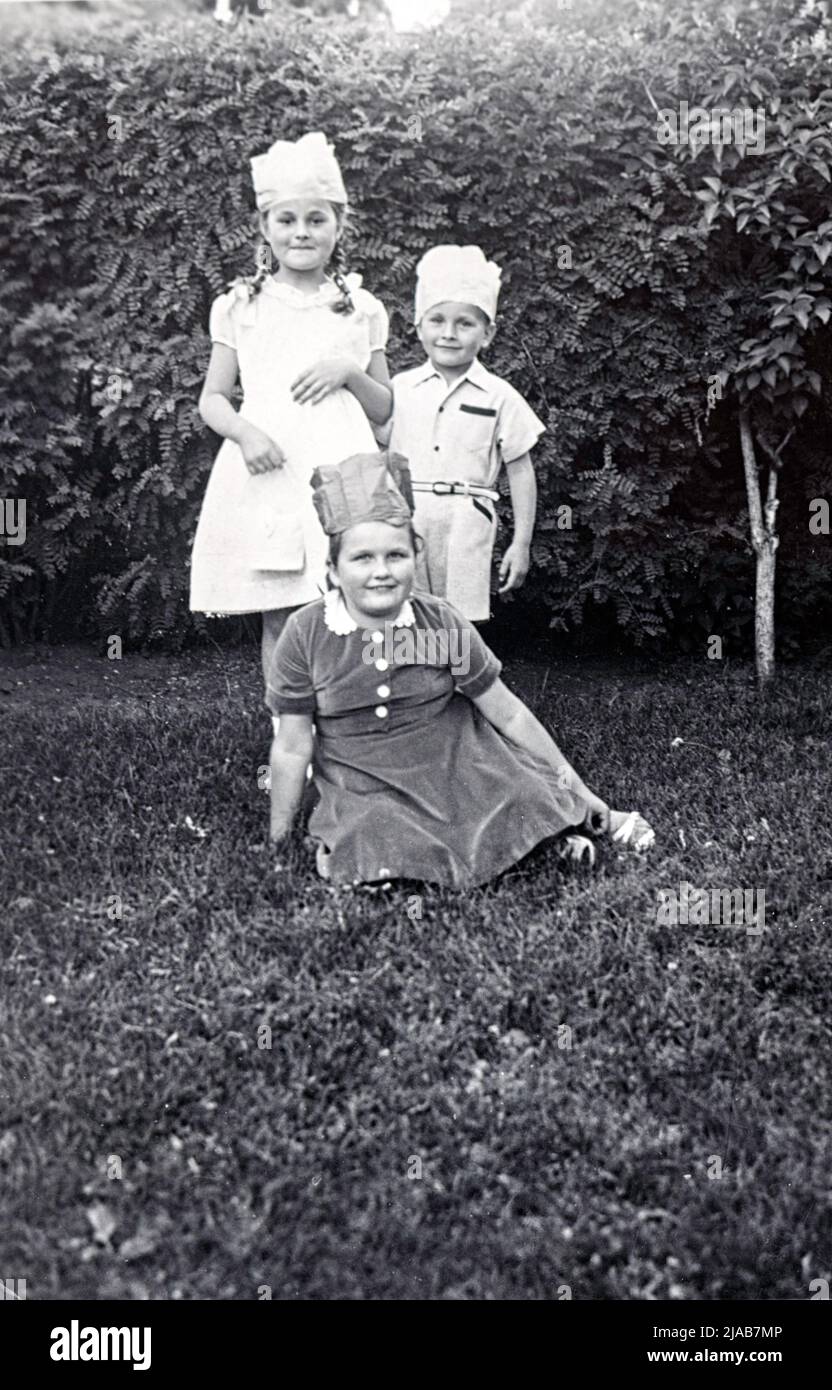 Three young birthday party guests wearing paper party hats. 1959 Stock ...