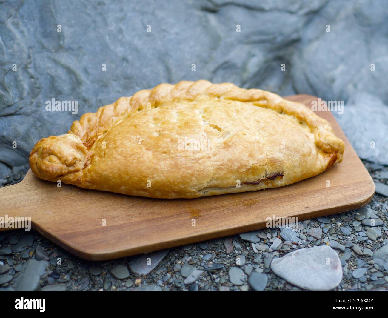Cornish pasty on wooden plate on rocky beach Stock Photo - Alamy