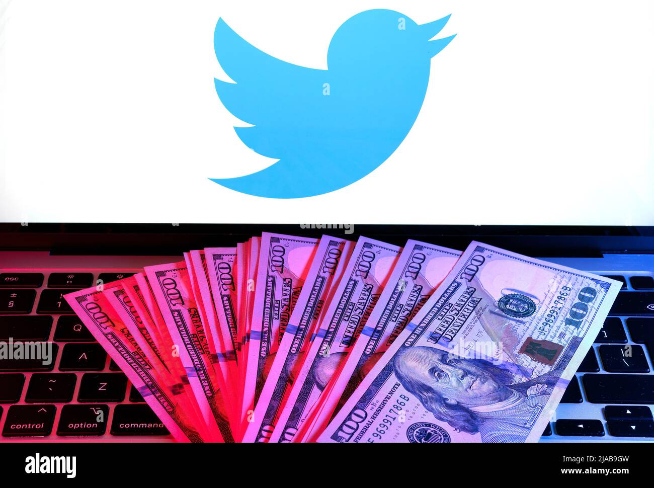 Dollar banknotes lit with red and blue light placed on laptop with ...