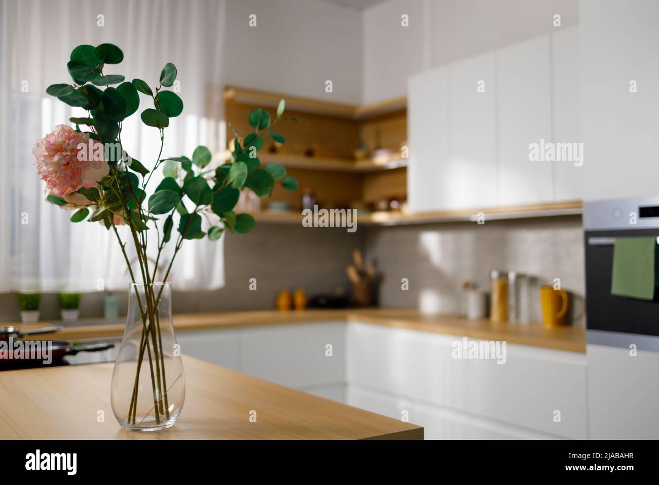 Artificial flowers in a glass vase stand on the table of a modern cozy ...