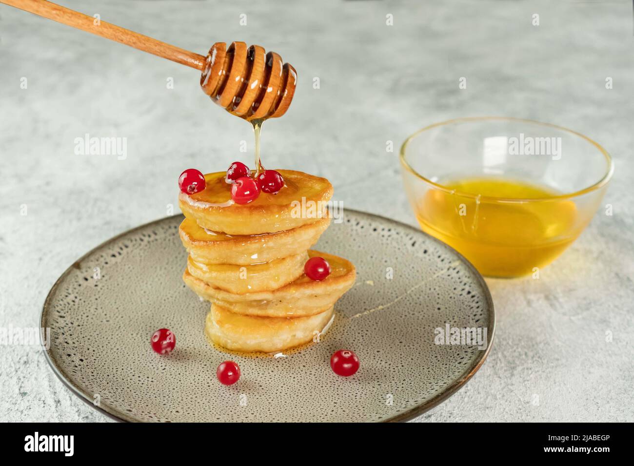 The hand holds a wooden stick pouring a stream of honey Stock Photo - Alamy