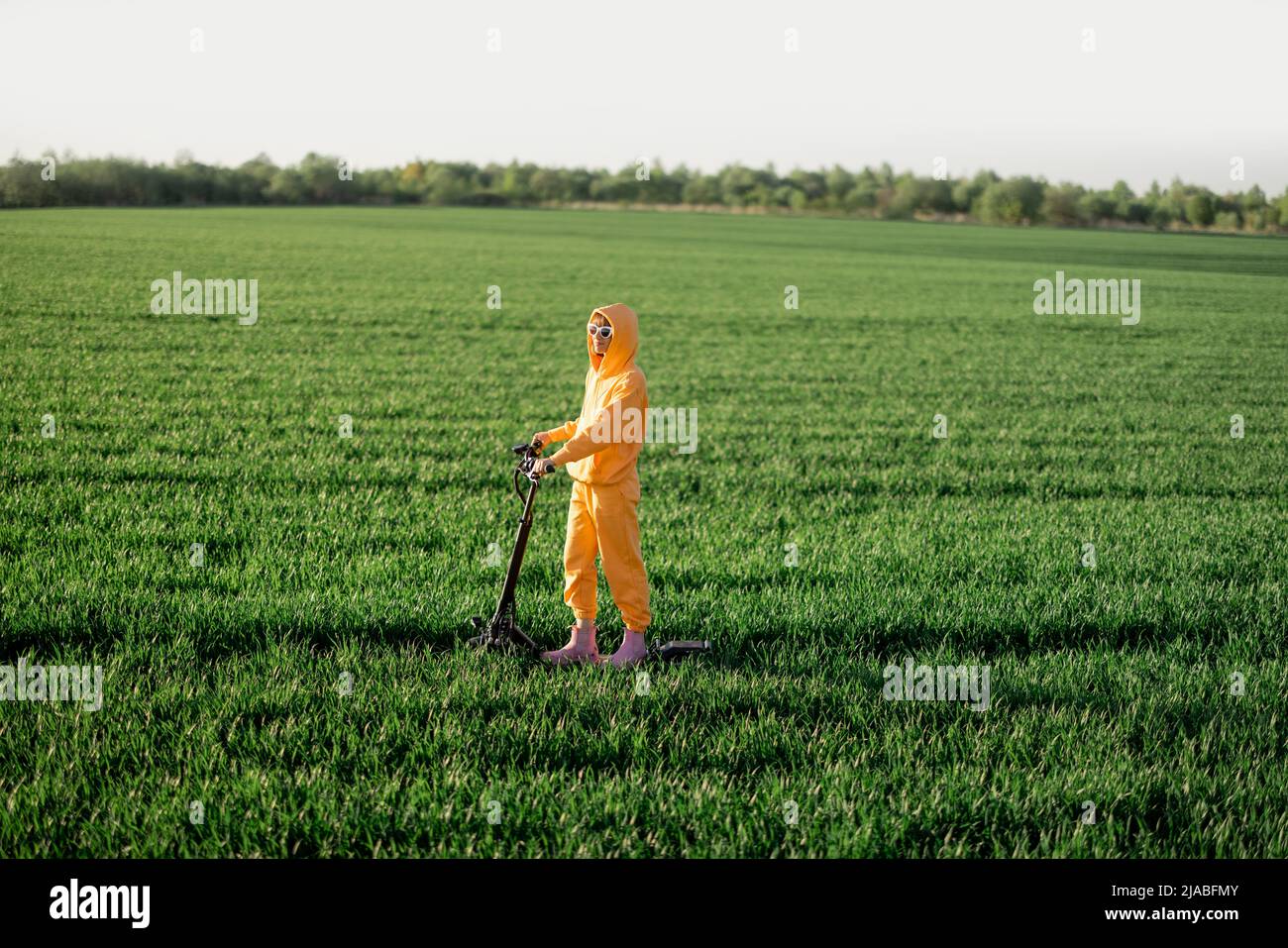 Person rides electric scooter on green field Stock Photo - Alamy