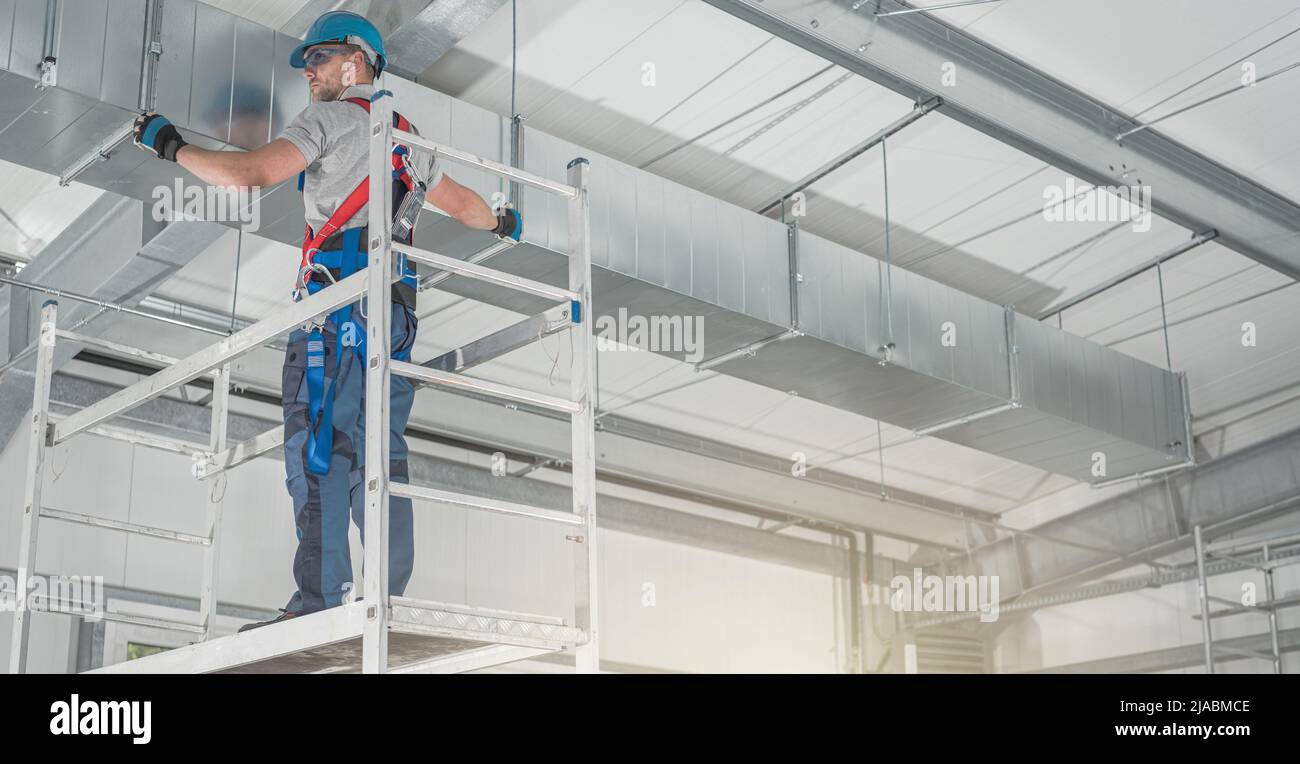 Professional HVAC Worker on a Aluminium Scaffolding Installing Air Duct ...