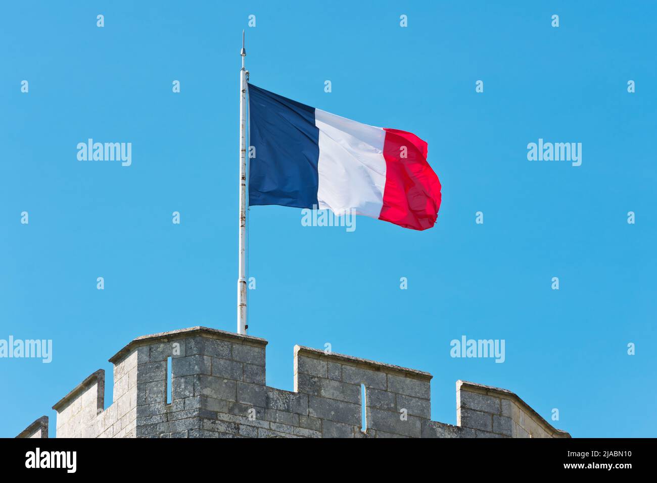 National Flag of France waving in the wind on top of historical castle of La Rochelle on clear ...