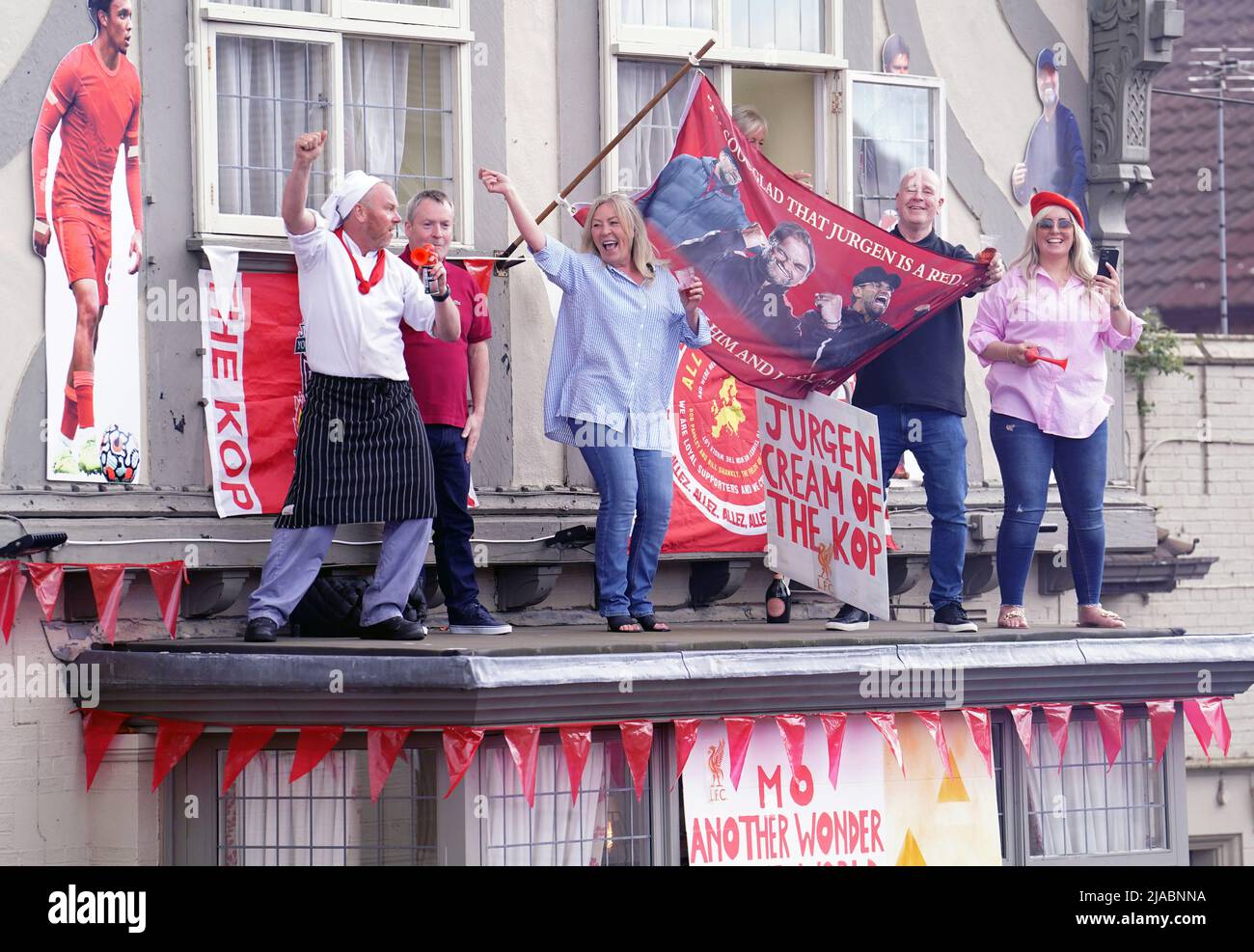Liverpool fans on a roof watch the team bus pass by during the trophy ...