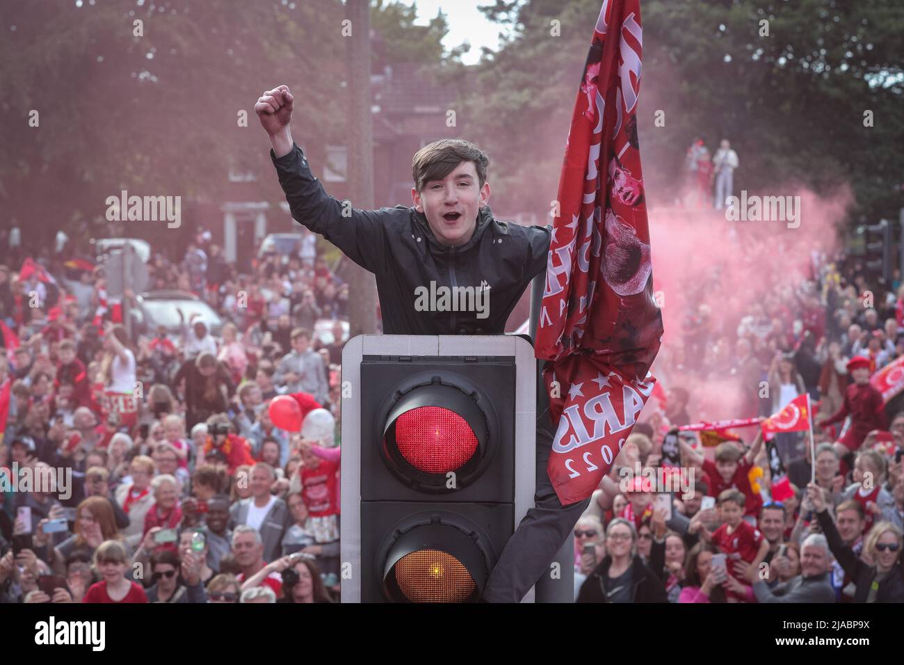 A supporter climbs on a traffic light as the Liverpool FC squad ...