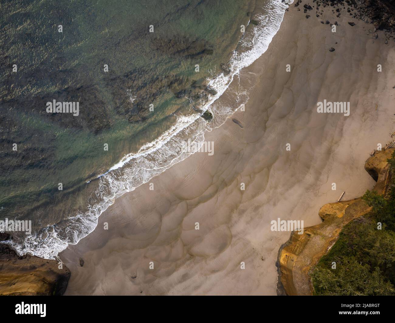 View from above. Dark ocean surface with light waves, sandy shore and ...