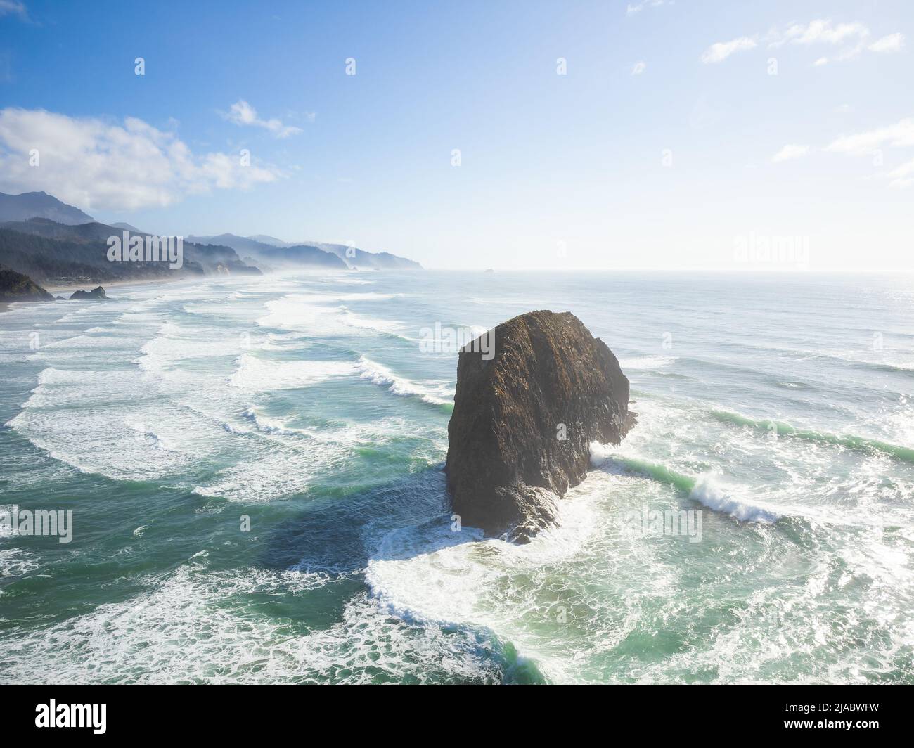Large stone, boulder in the ocean. A mountain range is visible in the ...