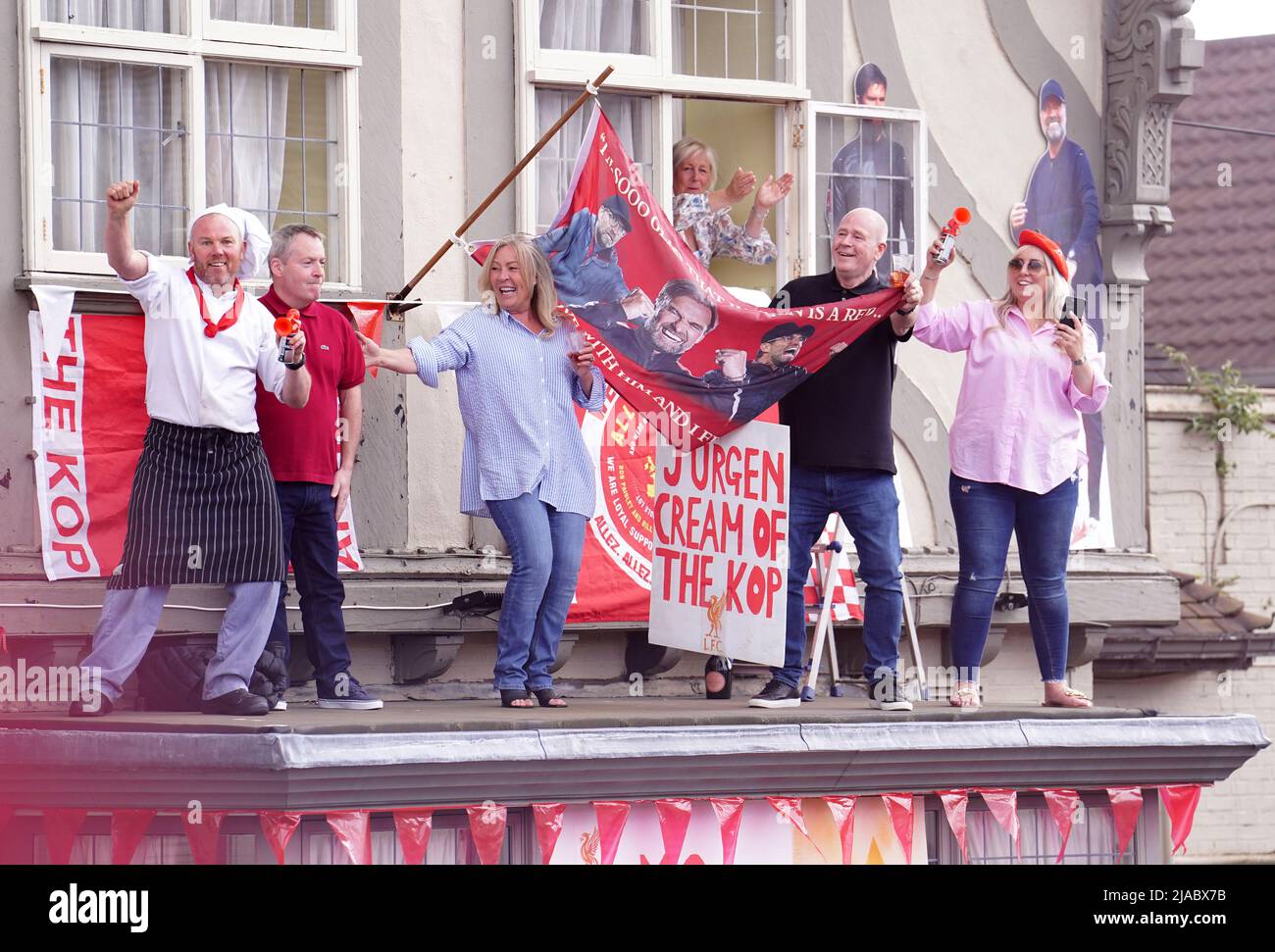 Liverpool fans on a roof watch the team bus pass by during the trophy ...