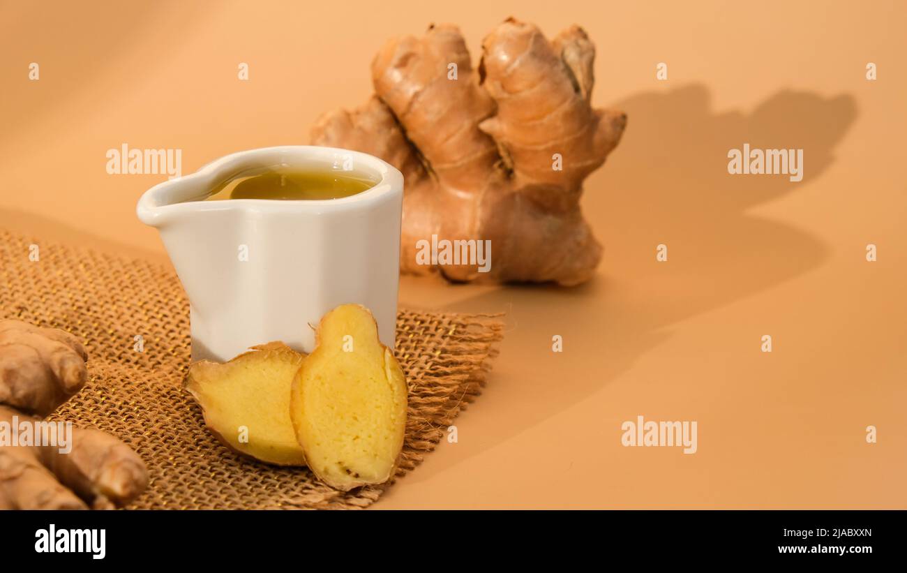 Sauce bowl of cooking ginger oil, ginger root on beige background ...