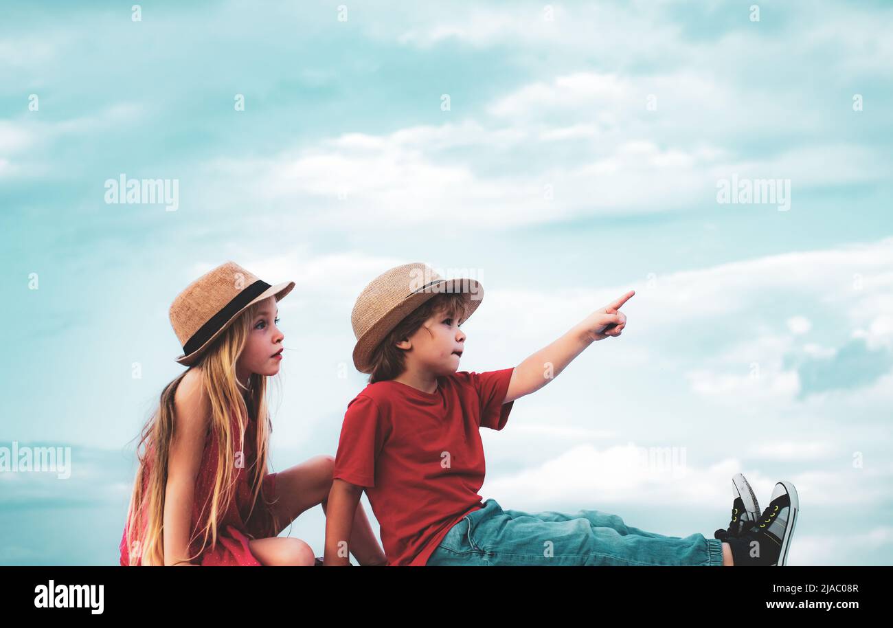 Charming kids on sky background. Cute little girl and boy. Posing outside. Emotions on the face ...
