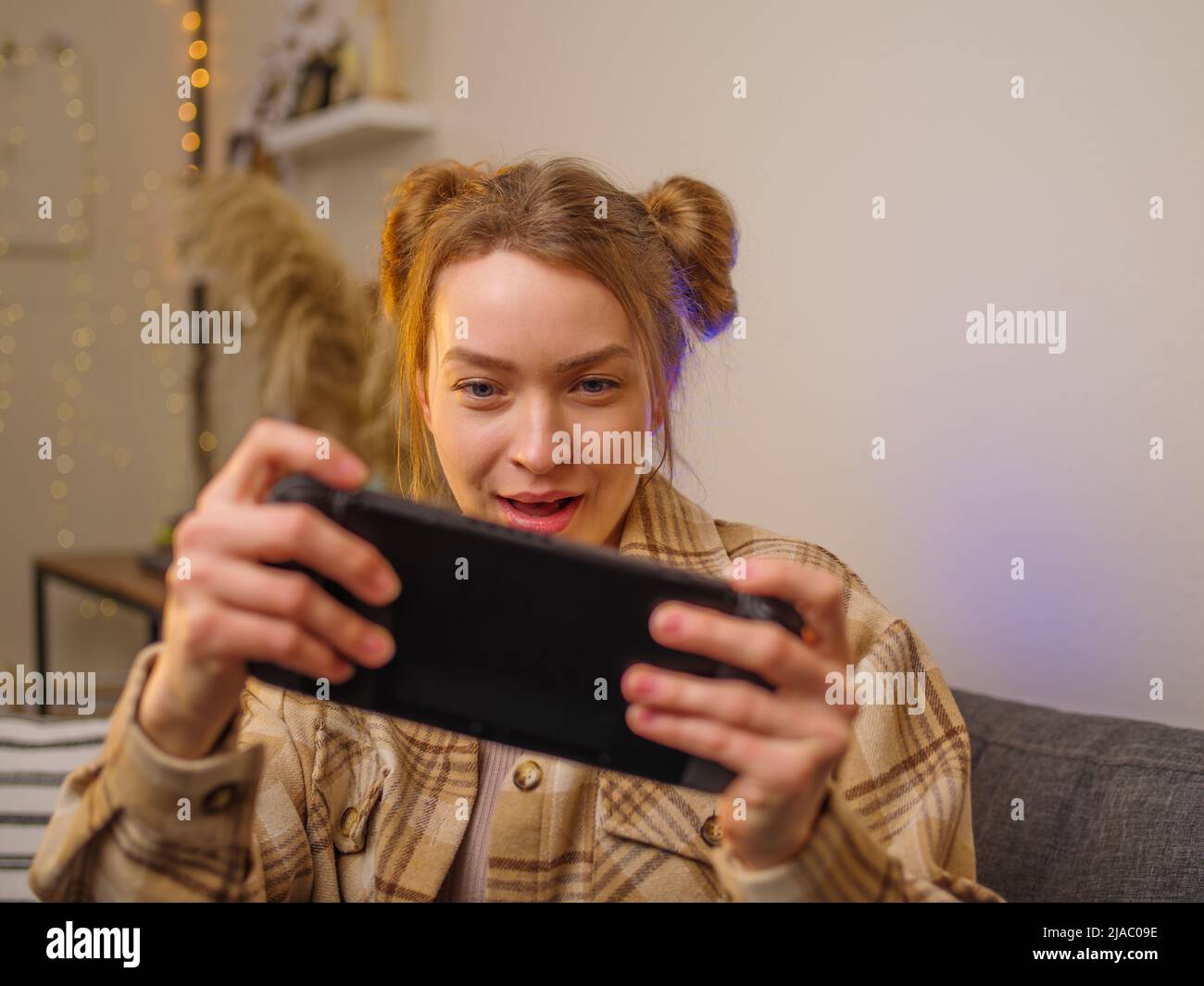Girl gamer enthusiastically plays a video game on a portable game ...