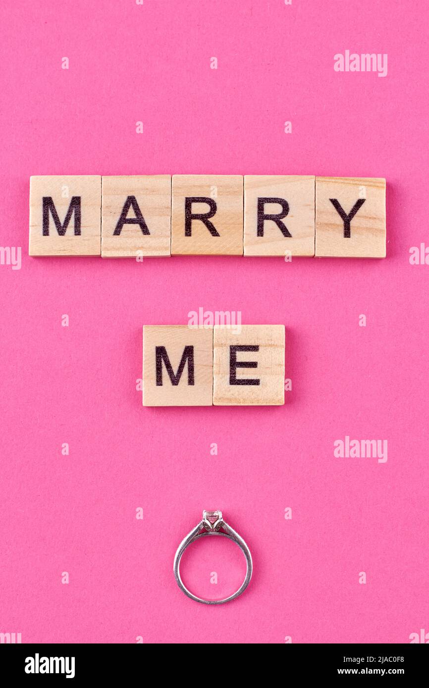 Flat lay top view of engagement ring and text marry me on wooden cubes ...