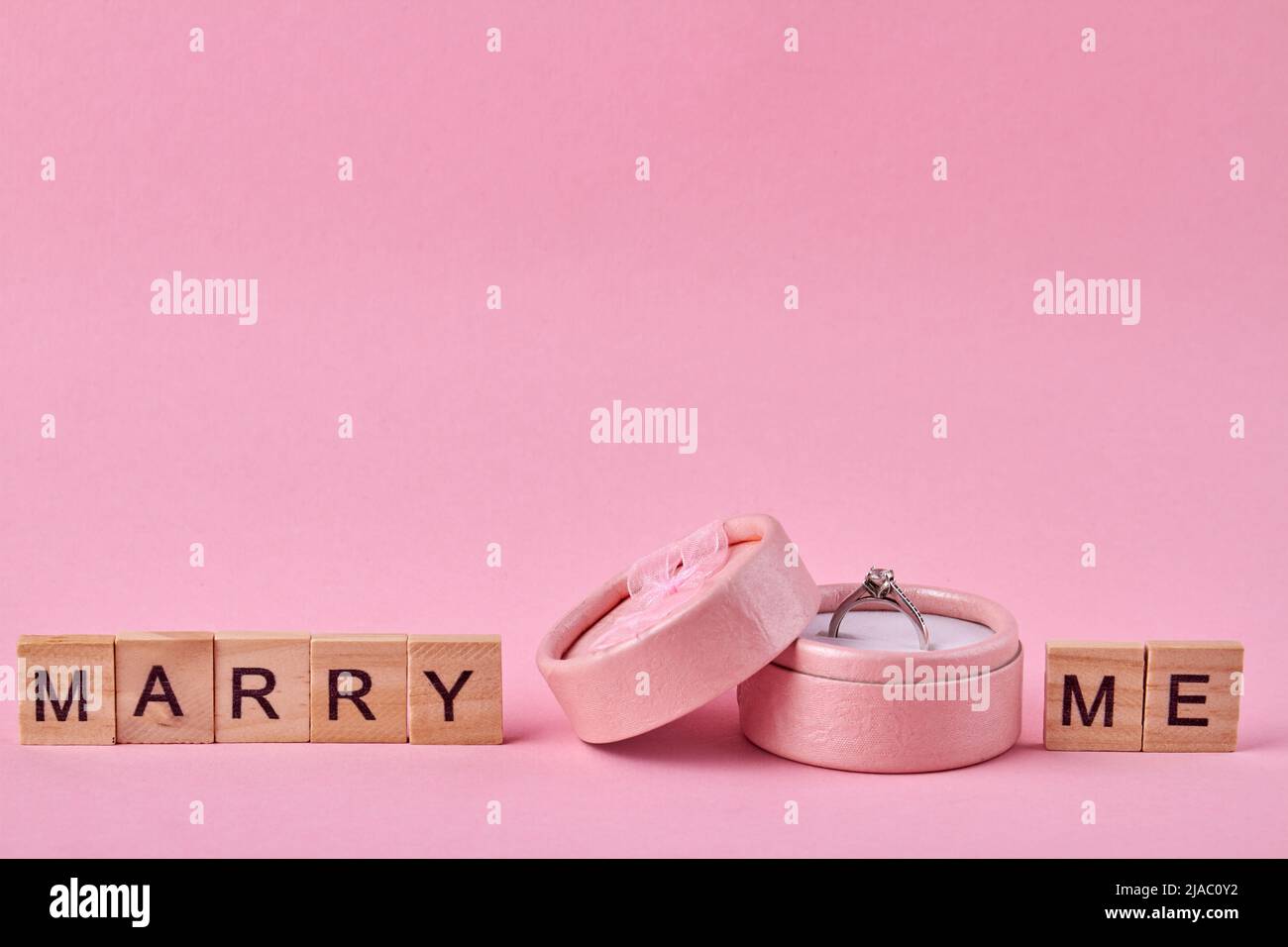 Marry me inscription and gift box with engagement ring. Pink background ...
