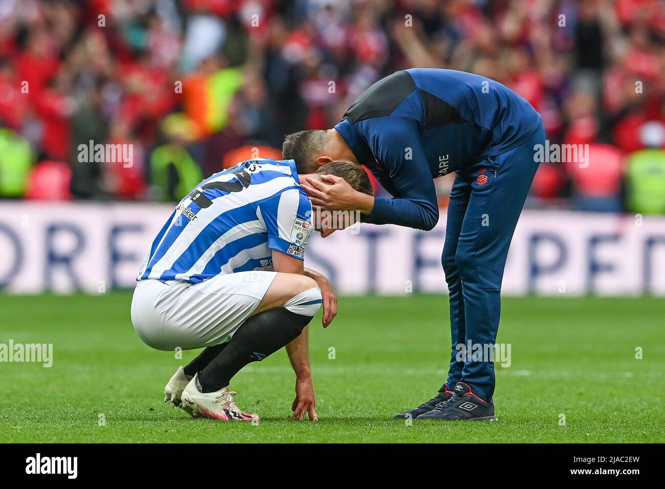 Tom Lees #32 of Huddersfield Town is consoled by a member of the ...