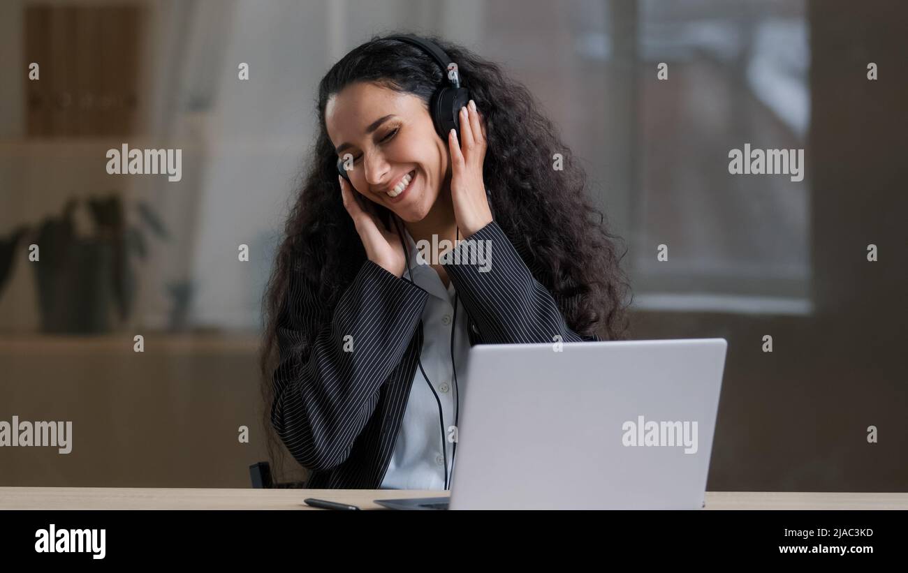 Happy young arabian lady woman freelancer in headphones listening loud ...
