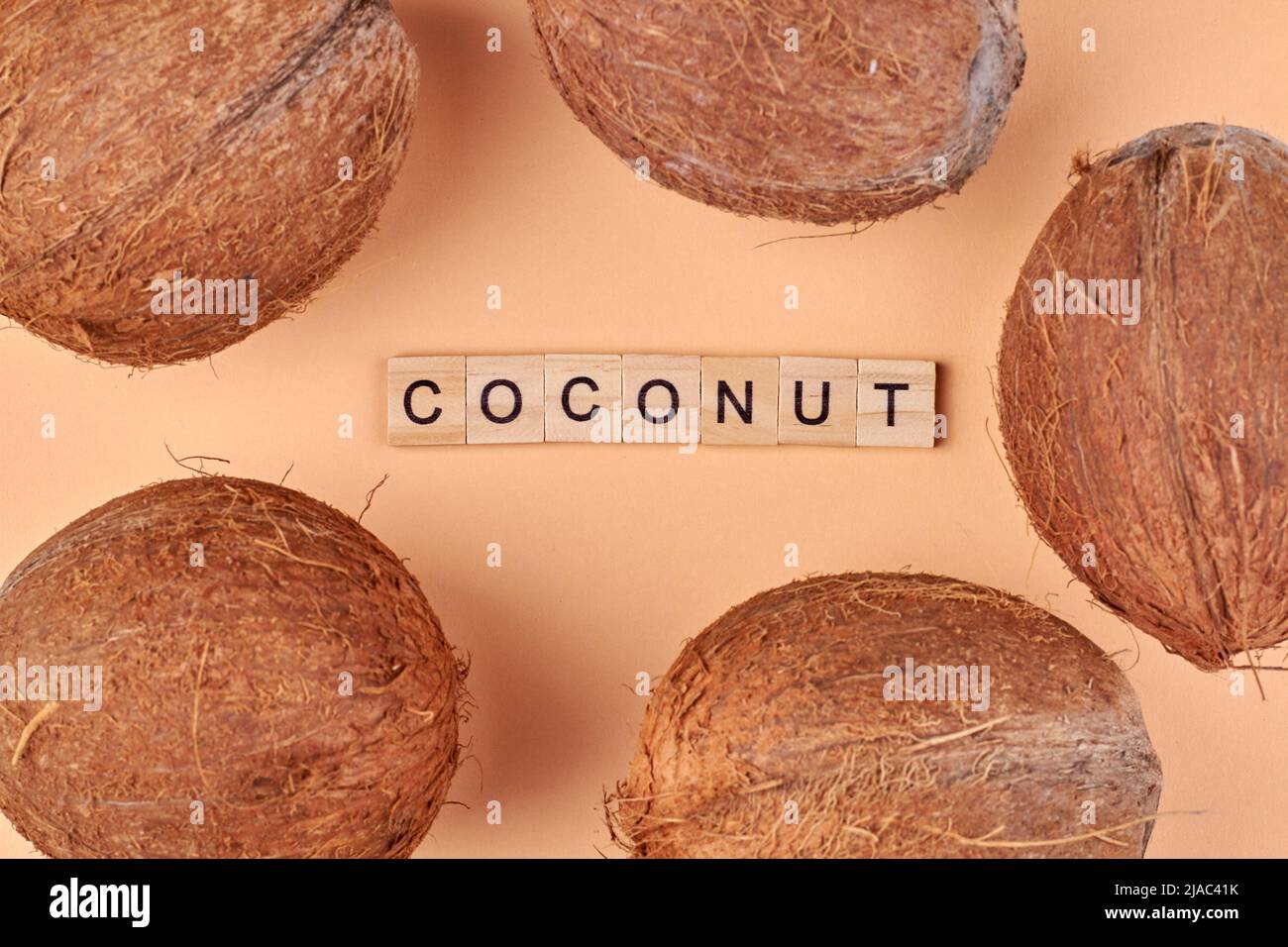 Five brown coconuts and inscription coconut from wooden cubes. Flat lay ...
