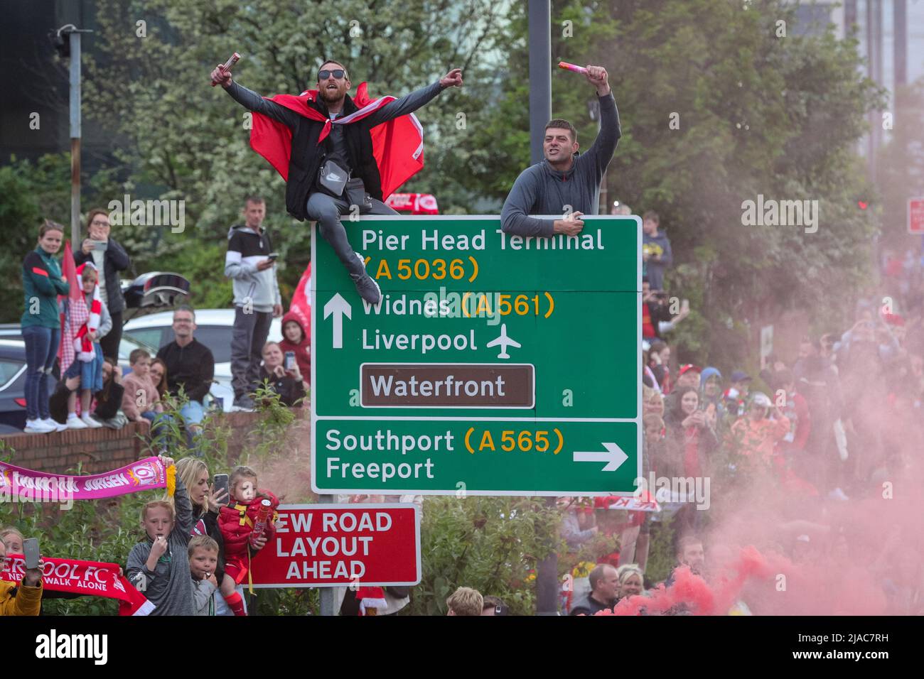Supporters climb on street signs and set of flares as the Liverpool FC ...
