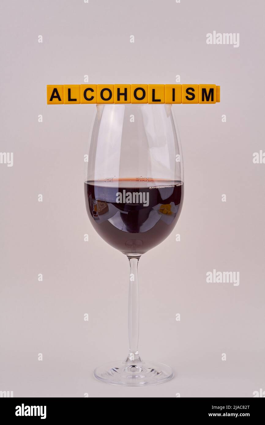 Glass of red wine and inscription alcoholism on plastic blocks ...