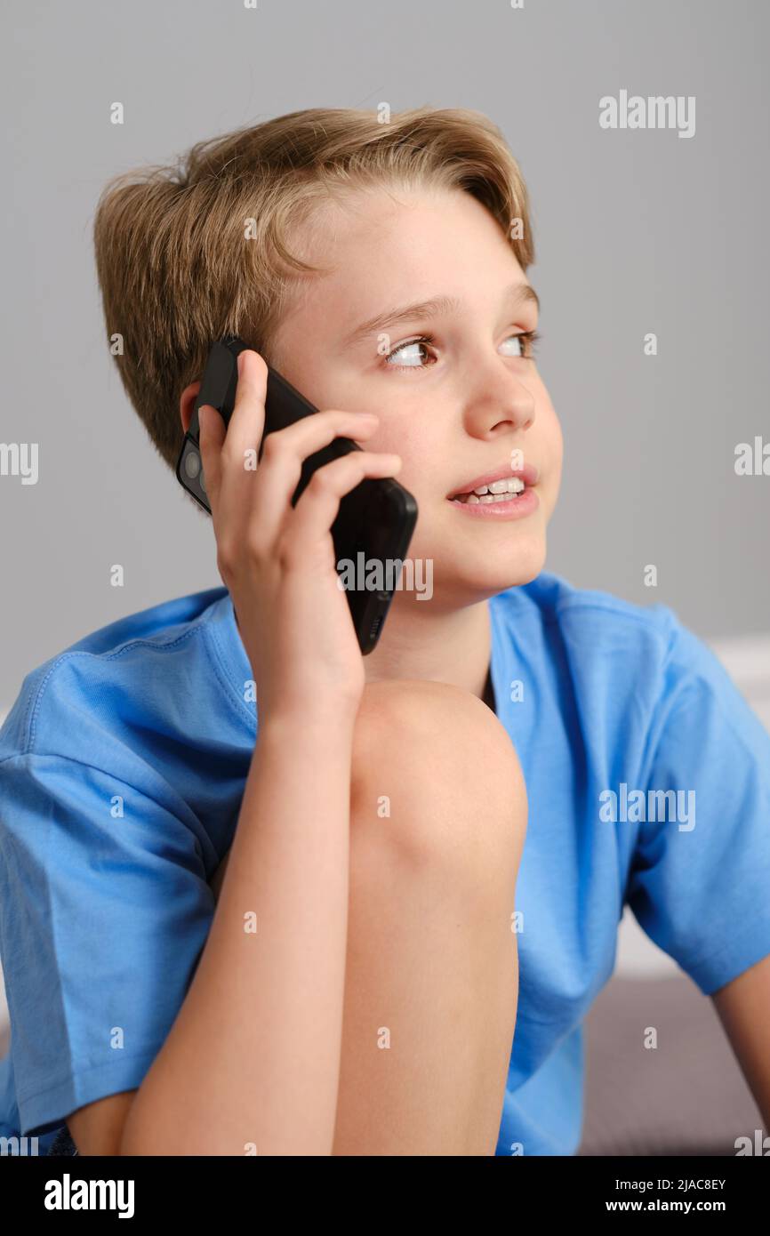 Generation Z boy talking on the phone at home. Portrait of a cute happy ...