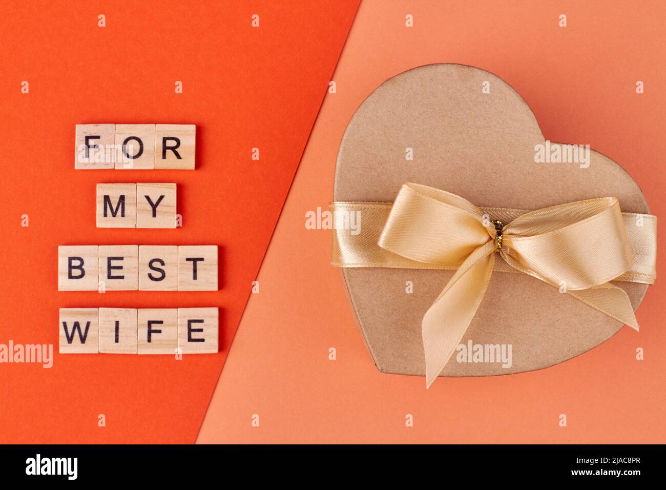 Heart-shaped gift box with beautiful bow on color background. Wooden ...