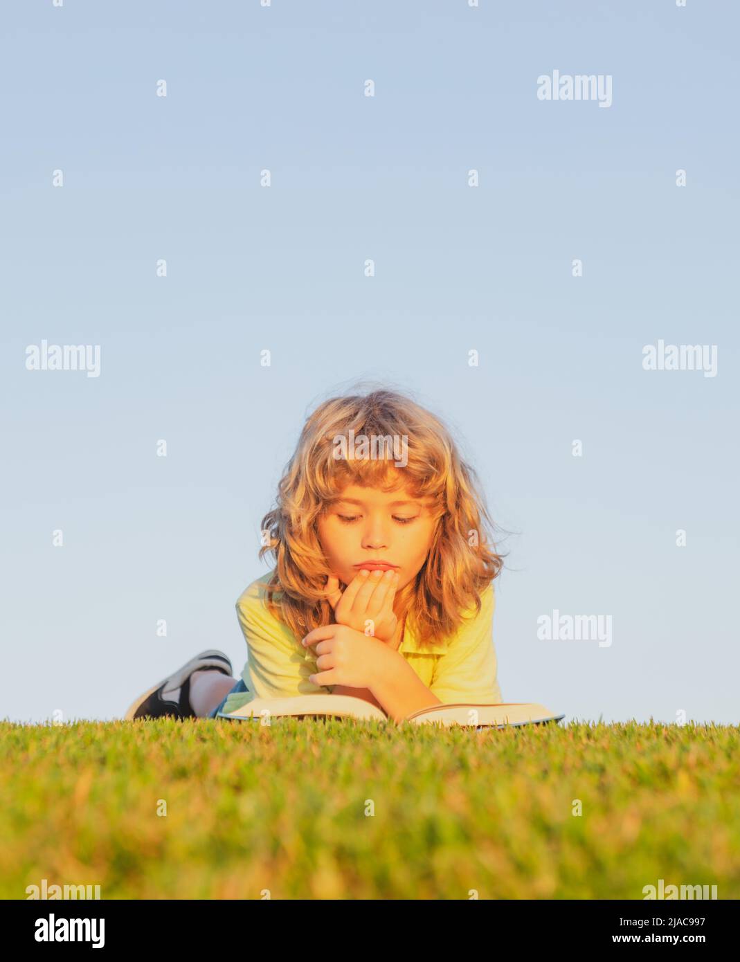 Cute kid reading book outside on grass. Outdoor school, learning kids ...