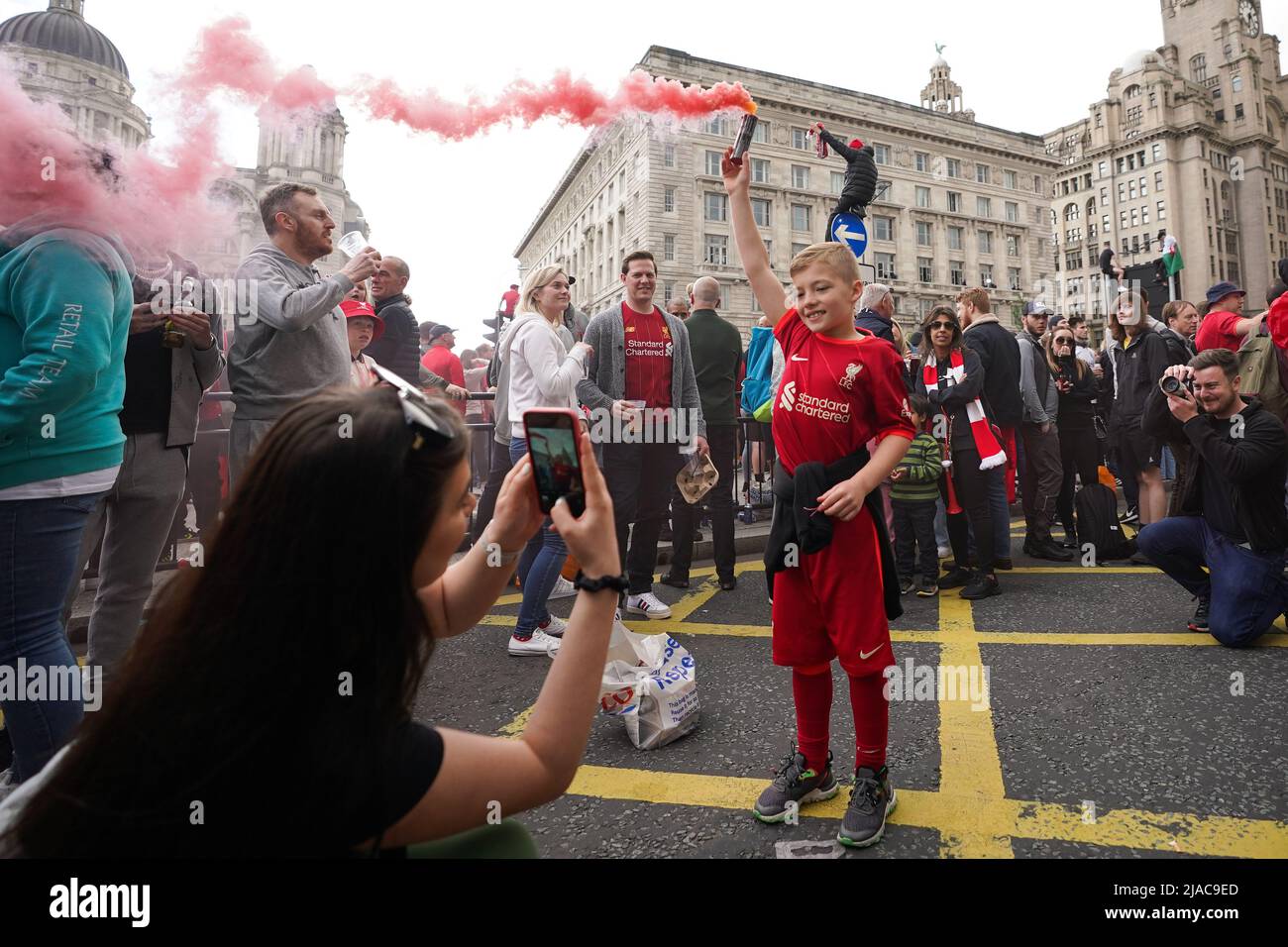 A young Liverpool fan holds a flare during the trophy parade in ...