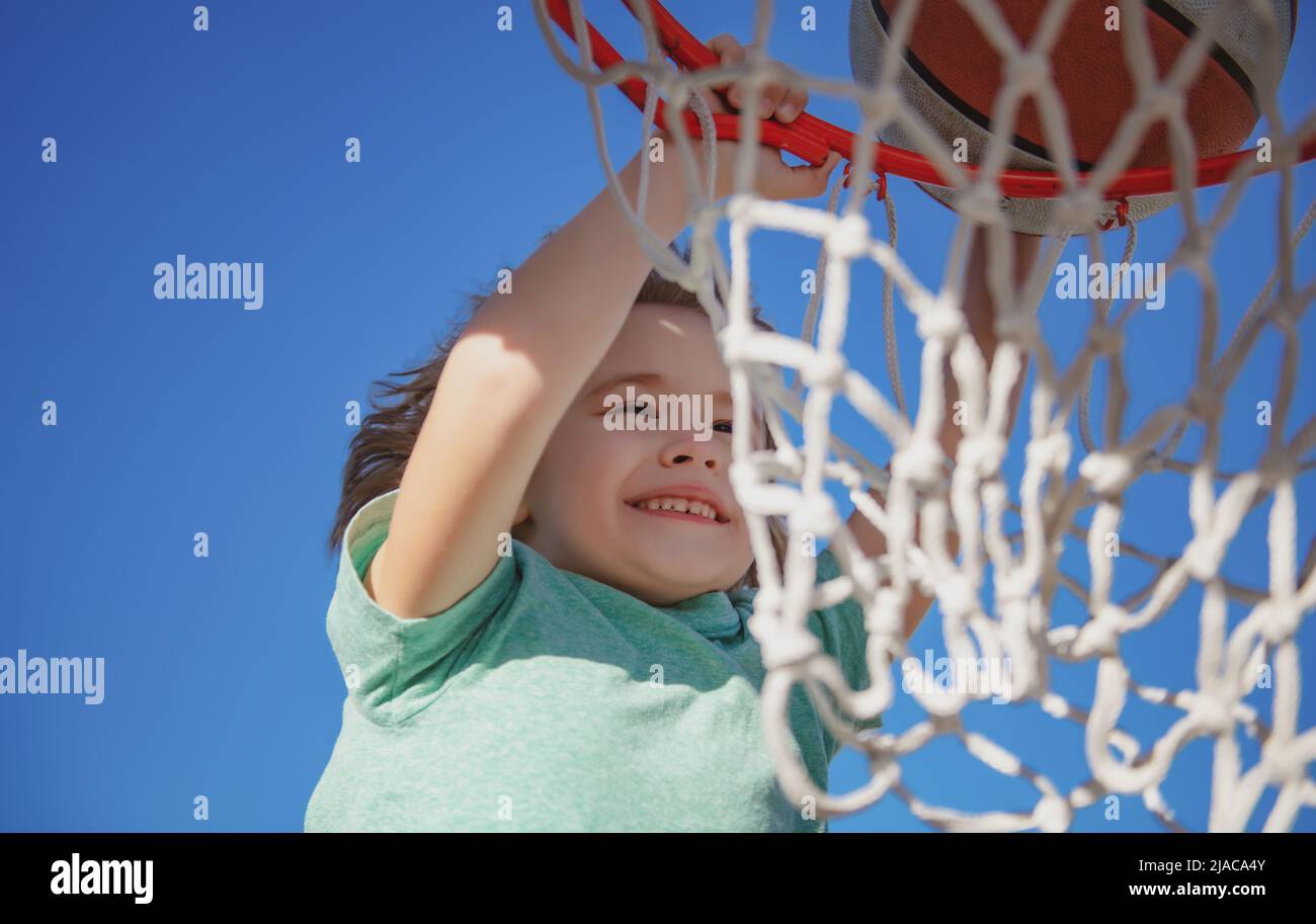 Cute smiling boy plays basketball and making slam dunk. Closeup ...