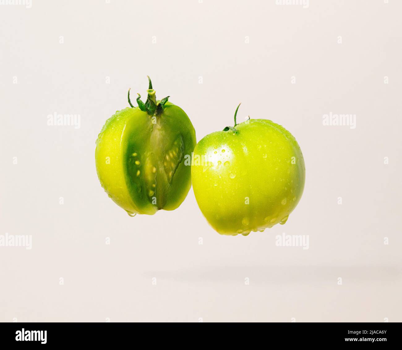 Green unripe tomato cut in half on grey background. Minimal food ...