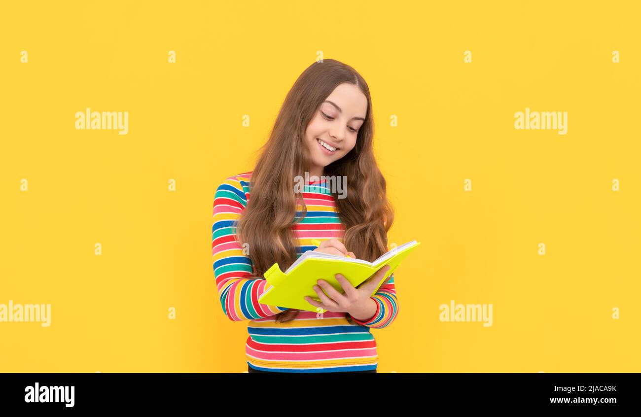 Happy girl child write down in copybook yellow background, writing ...