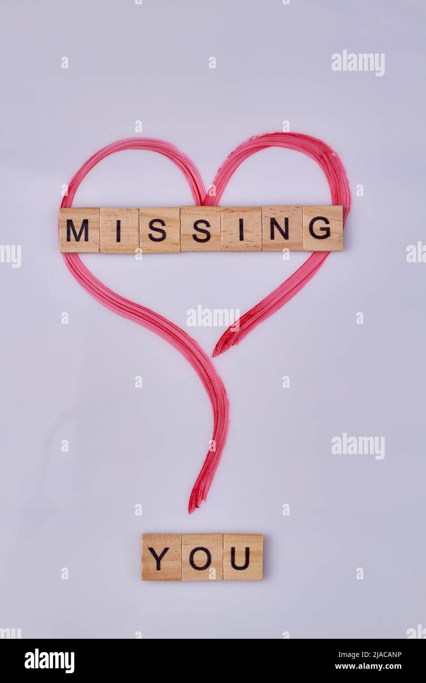 Missing you text on wooden cubes and hand drawn red heart. Love message ...