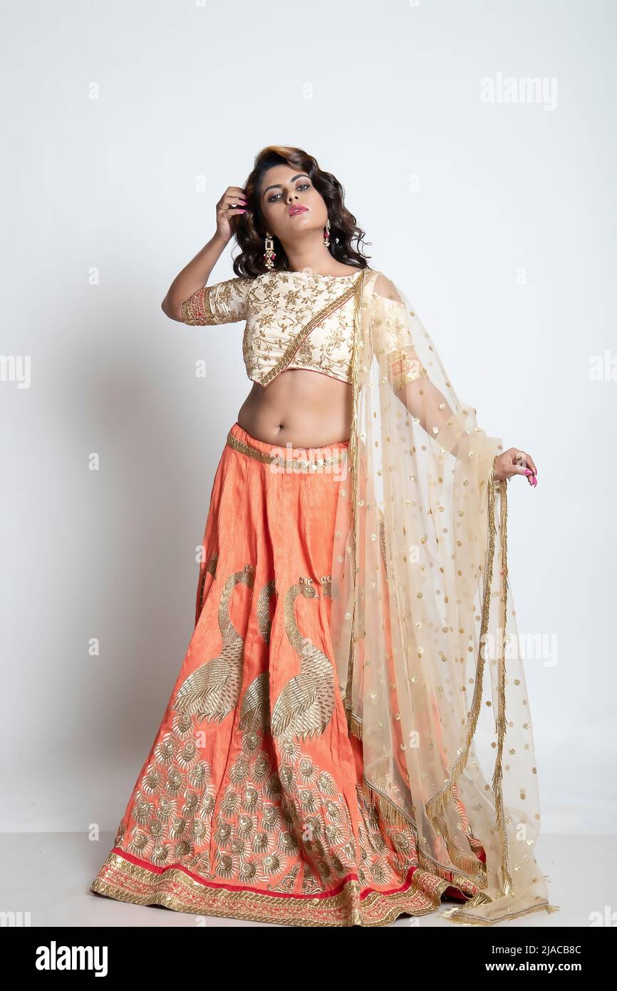 Indian female model wearing an orange and beige lehemga and jewellry ...