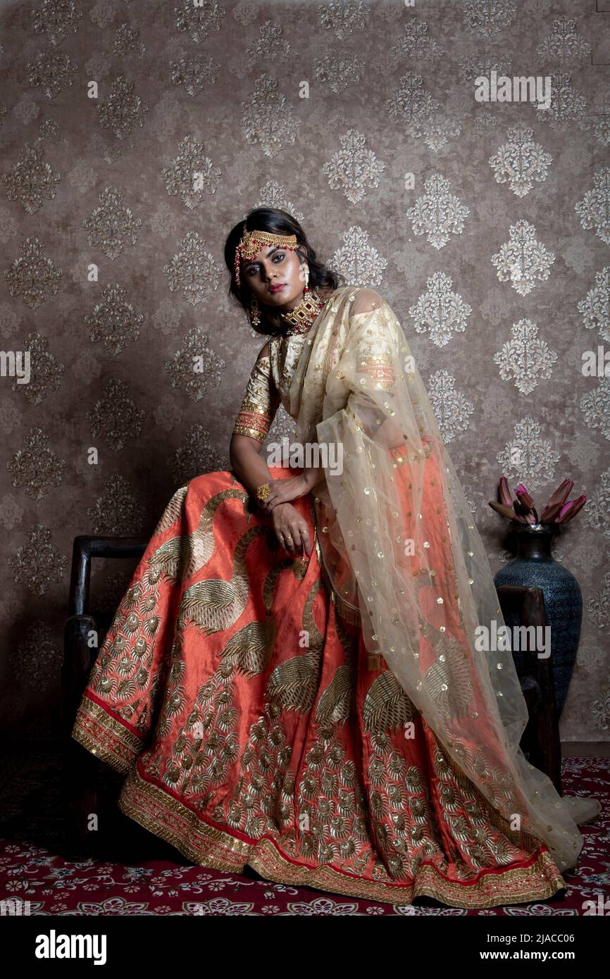 Indian female model wearing an orange and beige lehemga and jewellry ...
