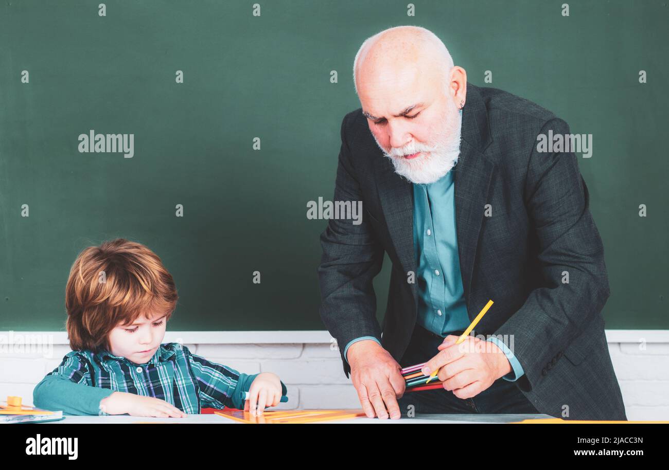 Elementary school teacher giving female pupil support in classroom ...