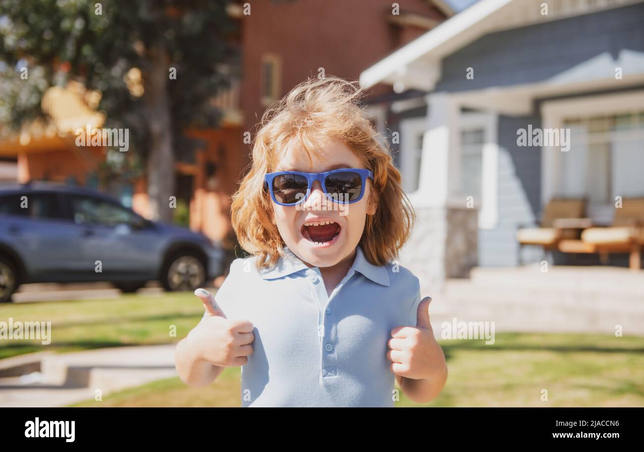 Excited kids portrait in sunglasses with thumbs up sign, close up head ...