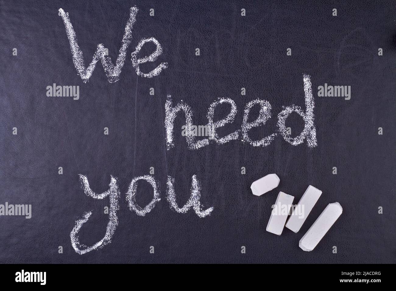 Handwritten chalk inscription We need you on black board. Asking ...