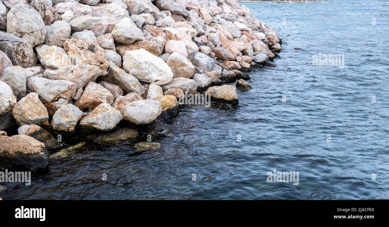 Rocky wall construction in blue ripple sea. Rough breakwater, seawall ...