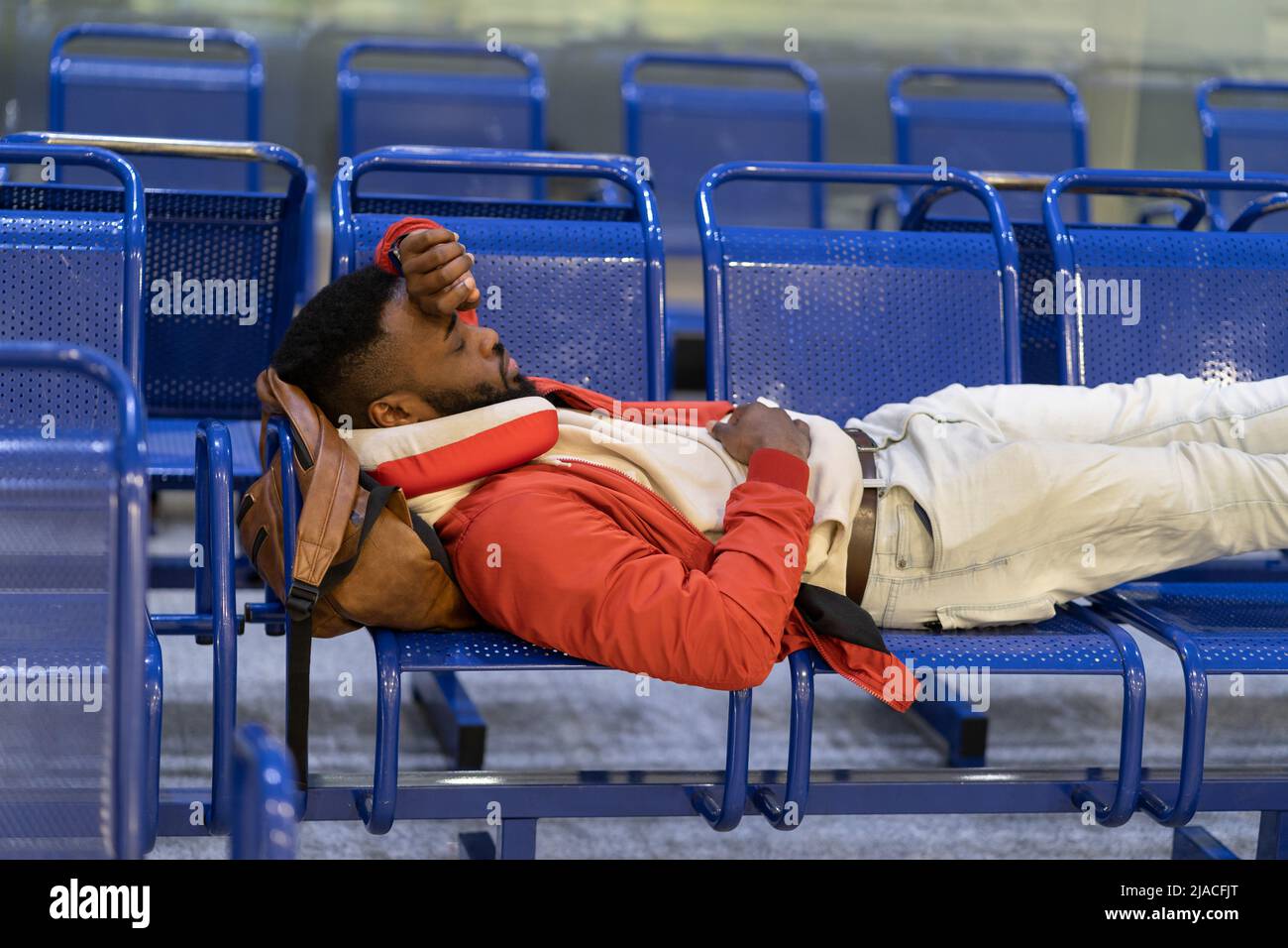 Exhausted African man napping while waiting for flight. Black guy lying ...