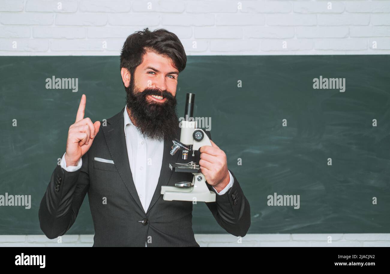 Friendly teacher in classroom near blackboard desk. Teacher is skilled ...