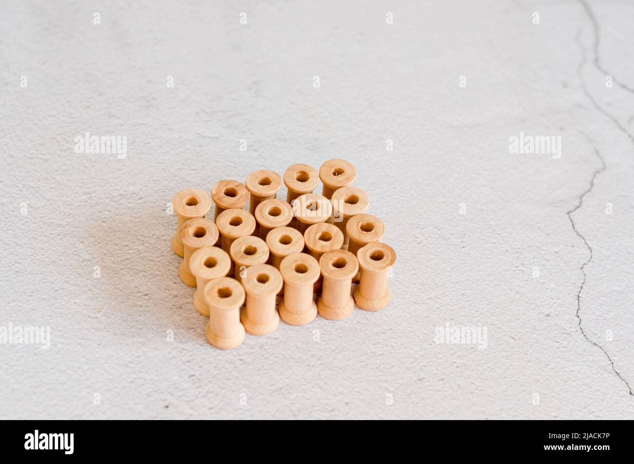 Many empty wooden thread spools lined up in ranks on gray concrete ...