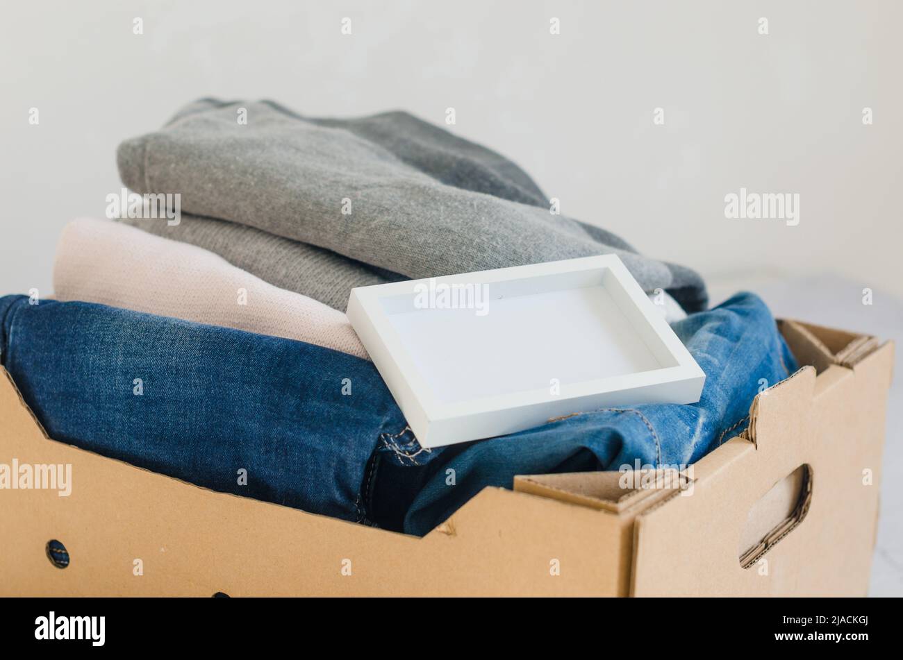 Cardbox with women's casual all-season clothes, sweaters and blue jeans ...