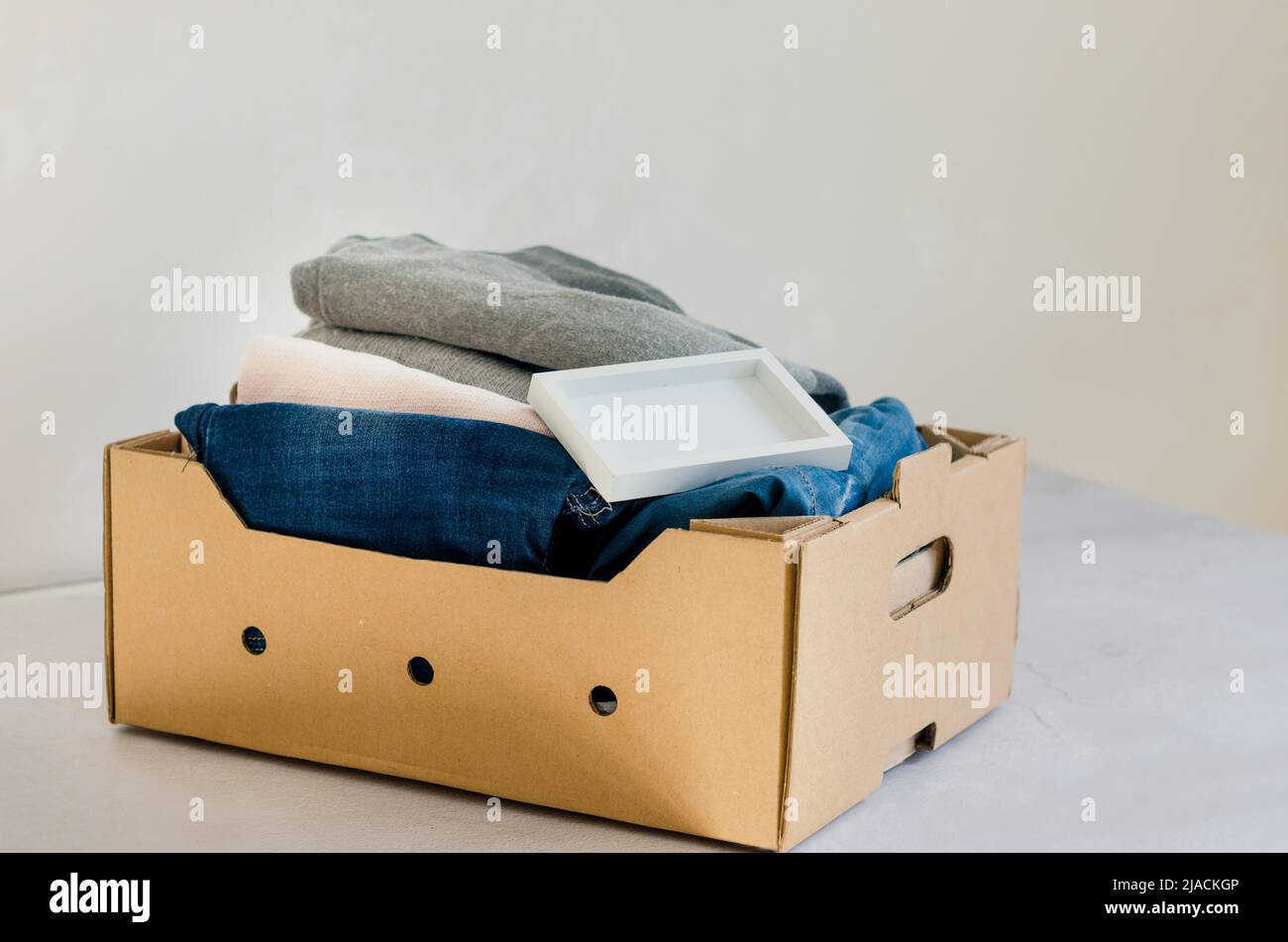 Cardbox with women's casual all-season clothes, sweaters and blue jeans ...