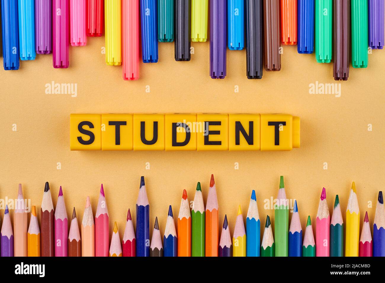 The word student written on cubes. Colorful pencils and felt pens on ...